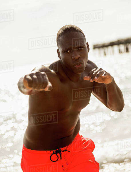 Mixed race man training on beach - Royalty-free Stock Photo | Dissolve