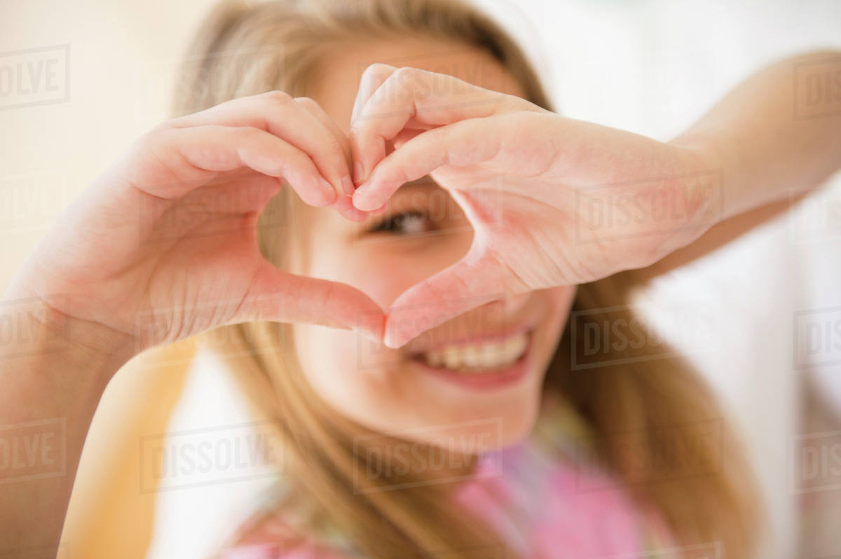 Caucasian girl making heart shape with hands - Stock Photo - Dissolve