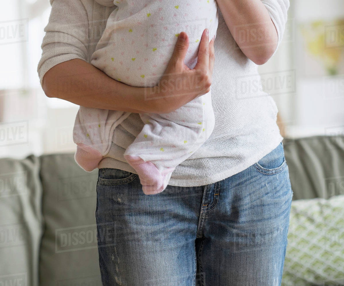 Asian mother holding baby in living room - Stock Photo - Dissolve
