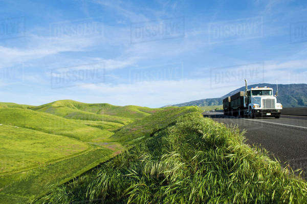 Truck driving on remote road in rolling landscape - Stock Photo - Dissolve