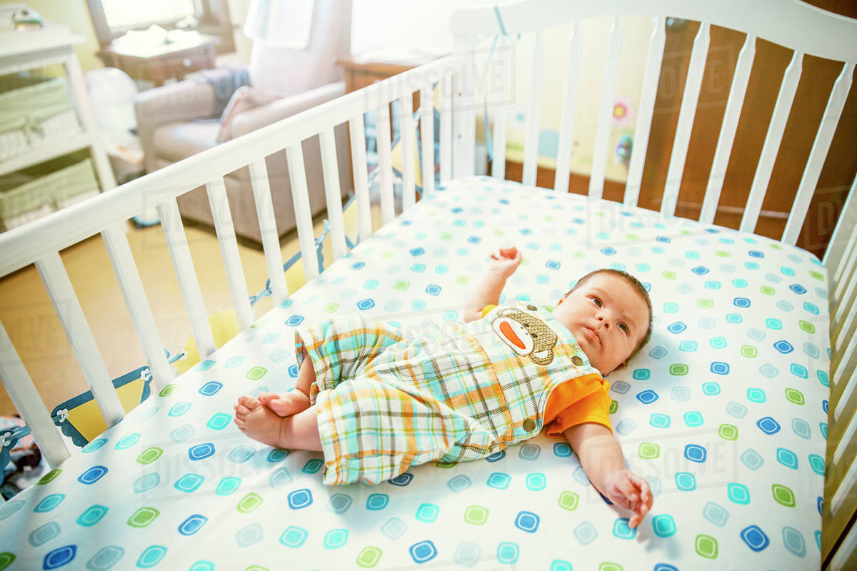Caucasian baby boy laying in crib - Stock Photo - Dissolve