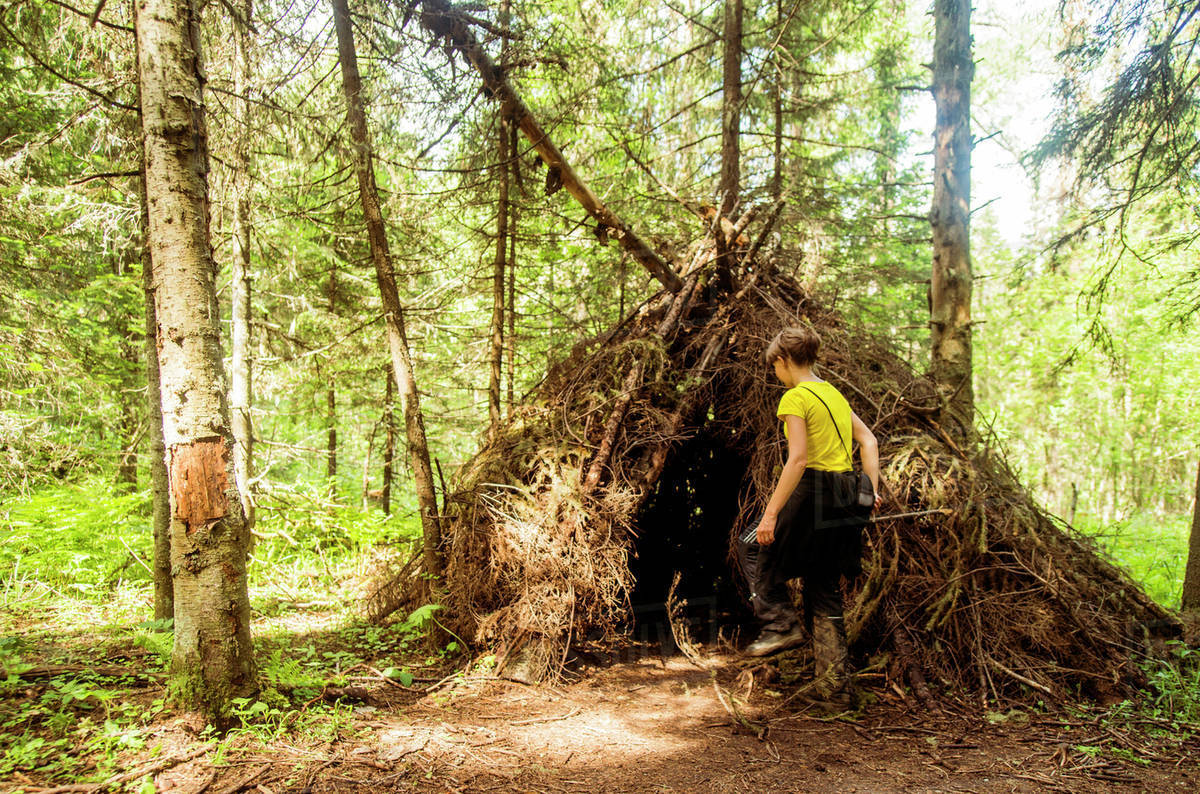 Caucasian boy playing in thatched teepee fort in forest - Royalty-free ...