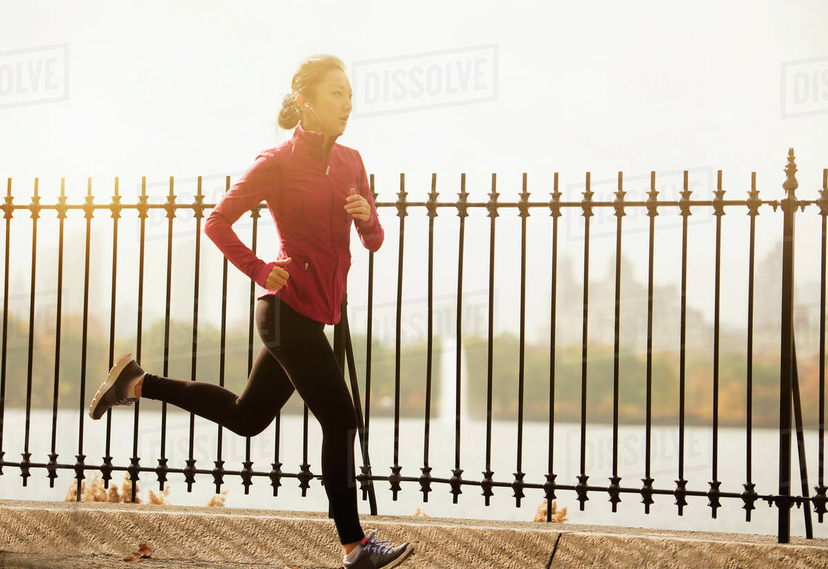 Asian woman running on waterfront path - Royalty-free Stock Photo ...