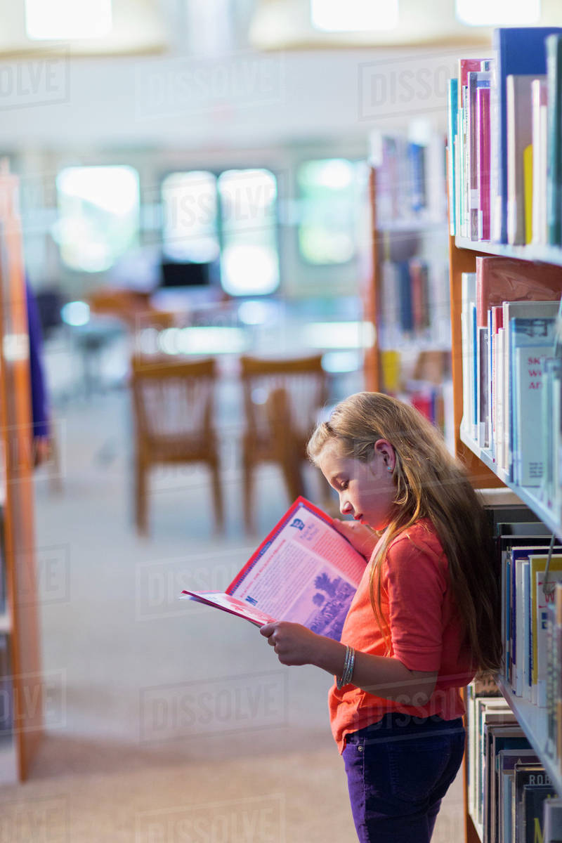 Caucasian student reading book in library - Stock Photo - Dissolve