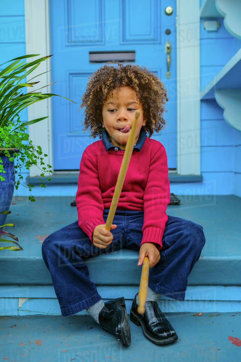 Pacific Islander boy with drumsticks sitting on front stoop - Royalty ...