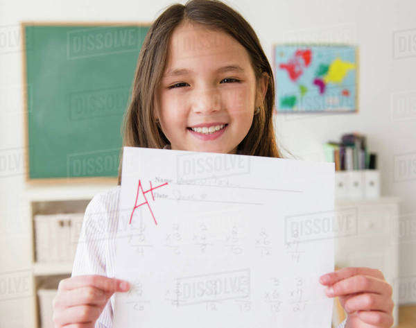 Mixed race girl holding paper with A+ grade - Stock Photo - Dissolve