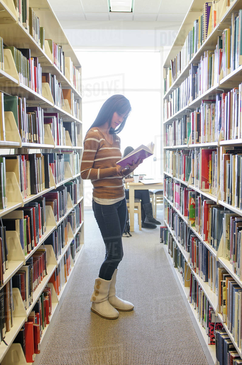 Student reading in library - Stock Photo - Dissolve