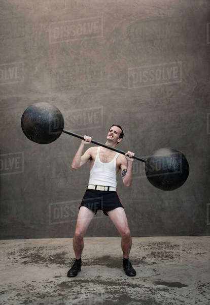 Skinny Caucasian weight lifter straining - Stock Photo - Dissolve