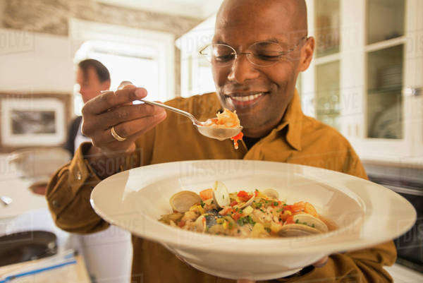 African American man eating seafood stew - Stock Photo - Dissolve