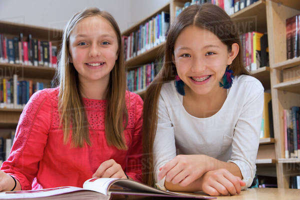 Female students smiling in library - Royalty-free Stock Photo | Dissolve