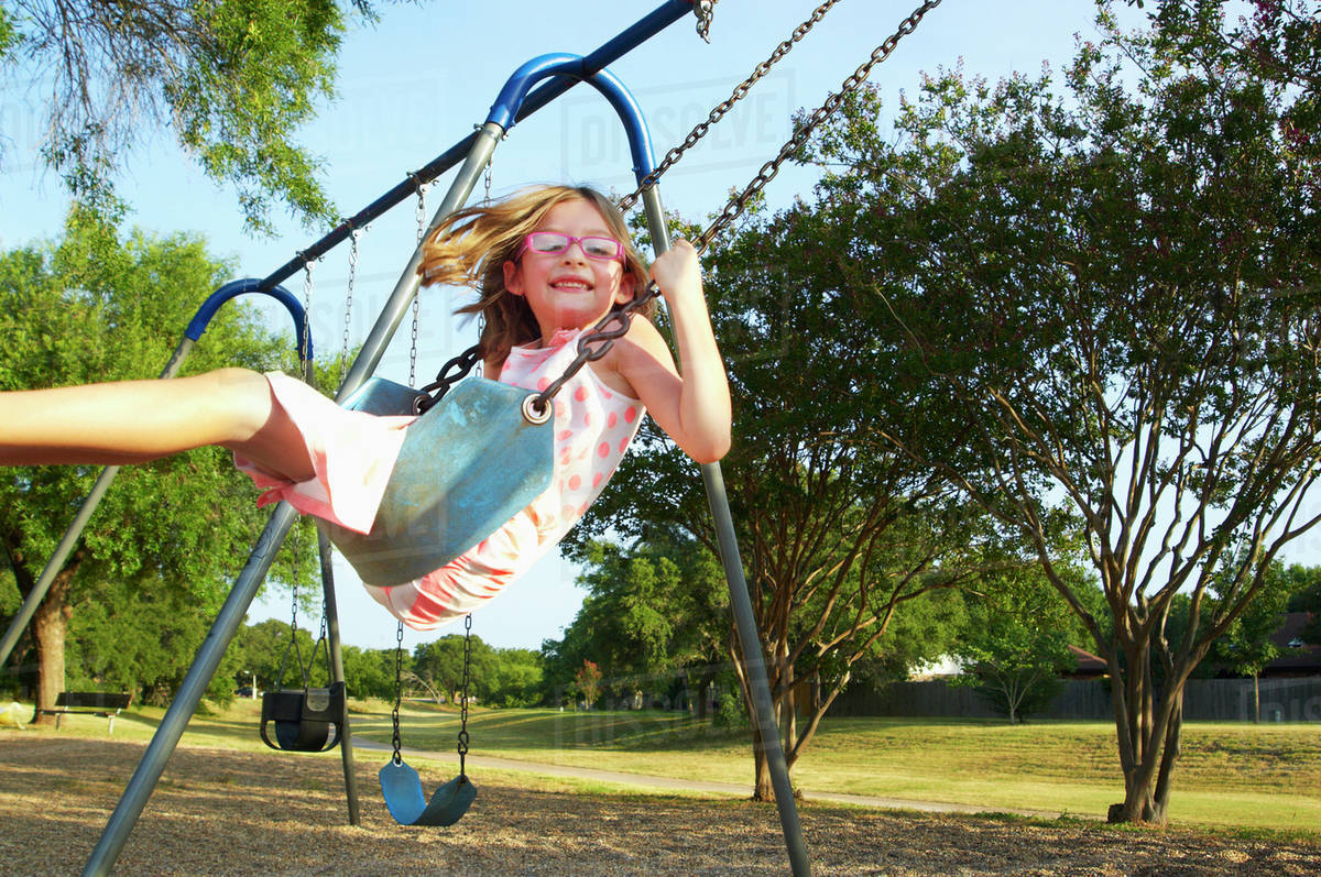 Hispanic playing on swings in park - Royalty-free Stock Photo | Dissolve