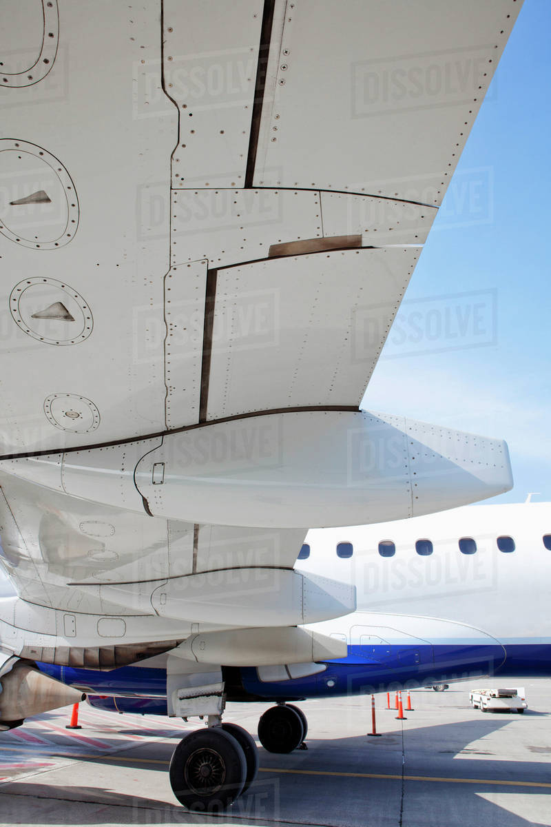 Close up of airplane wing on runway - Stock Photo - Dissolve