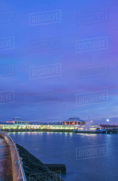 Harbor and boat lit up at dusk - Royalty-free Stock Photo | Dissolve