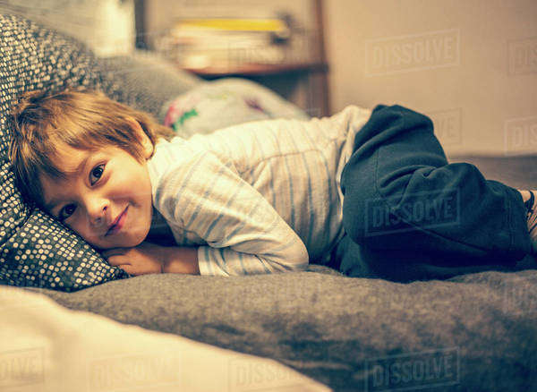 Mari boy smiling on bed - Stock Photo - Dissolve