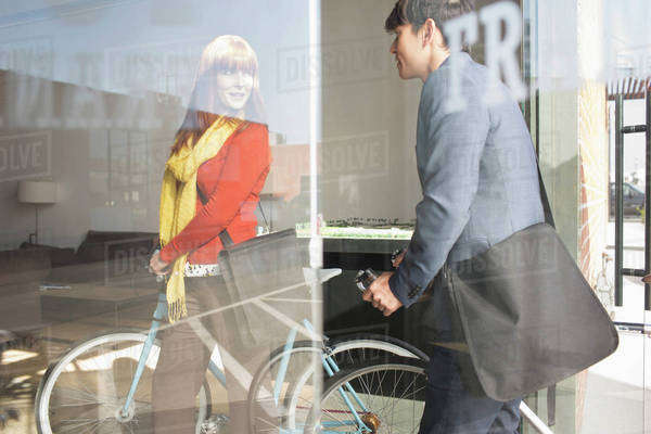 Business people wheeling bicycles in office - Stock Photo - Dissolve
