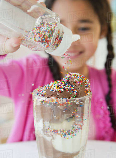 Mixed race girl putting sprinkles on ice cream - Royalty-free Stock ...