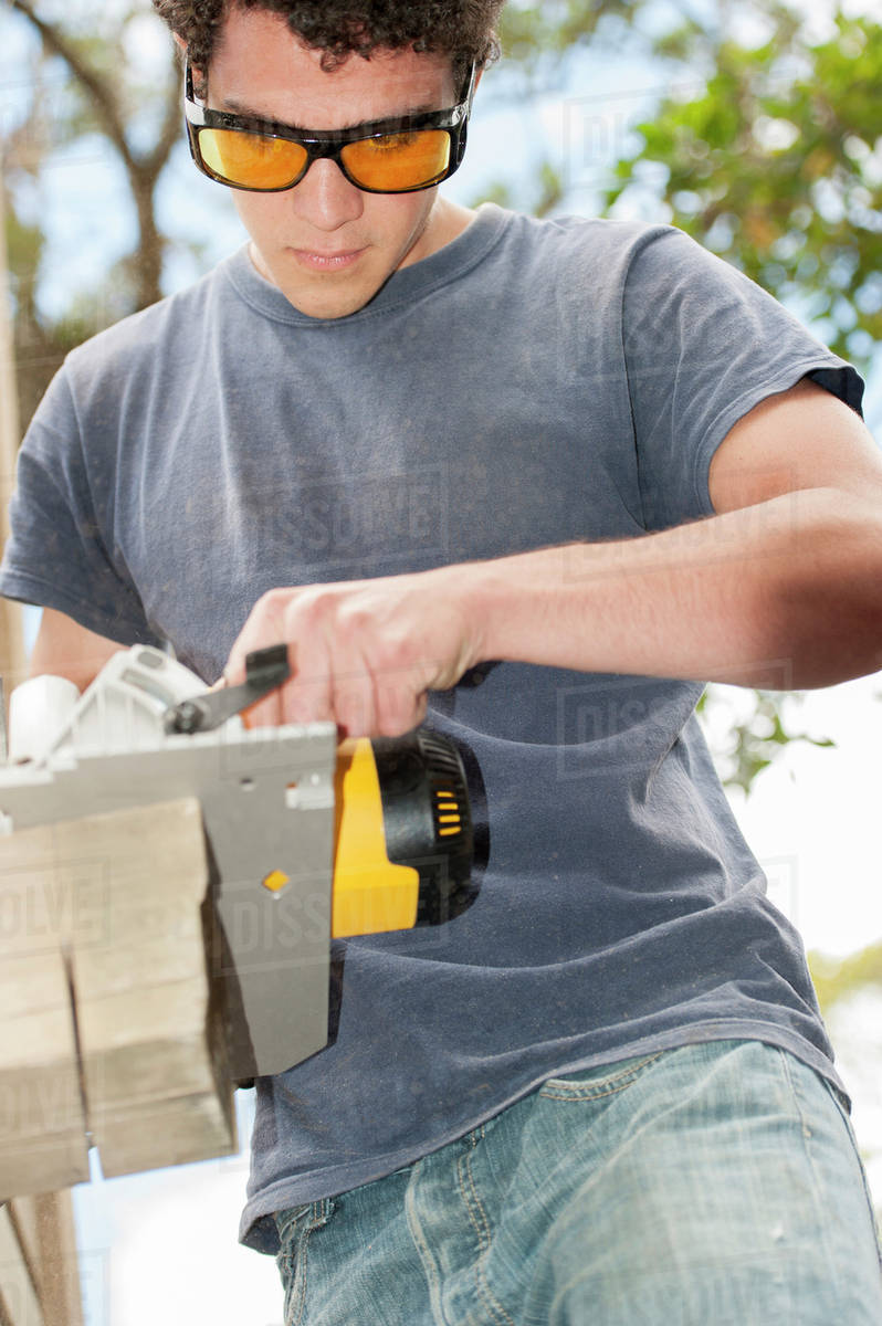 Hispanic man using saw - Stock Photo - Dissolve
