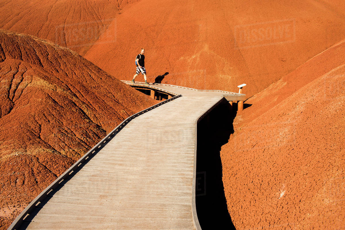 Caucasian hiker on wooden walkway in desert hills - Royalty-free Stock ...