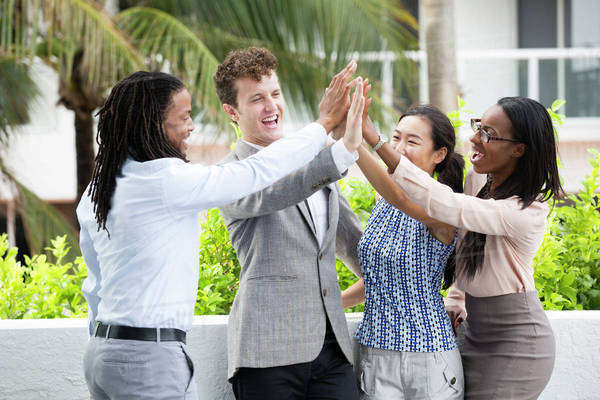 Business people high-fiving outdoors - Stock Photo - Dissolve