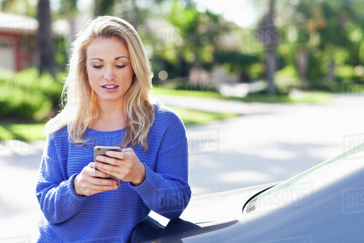 Caucasian woman using cell phone outside car - Royalty-free Stock Photo ...