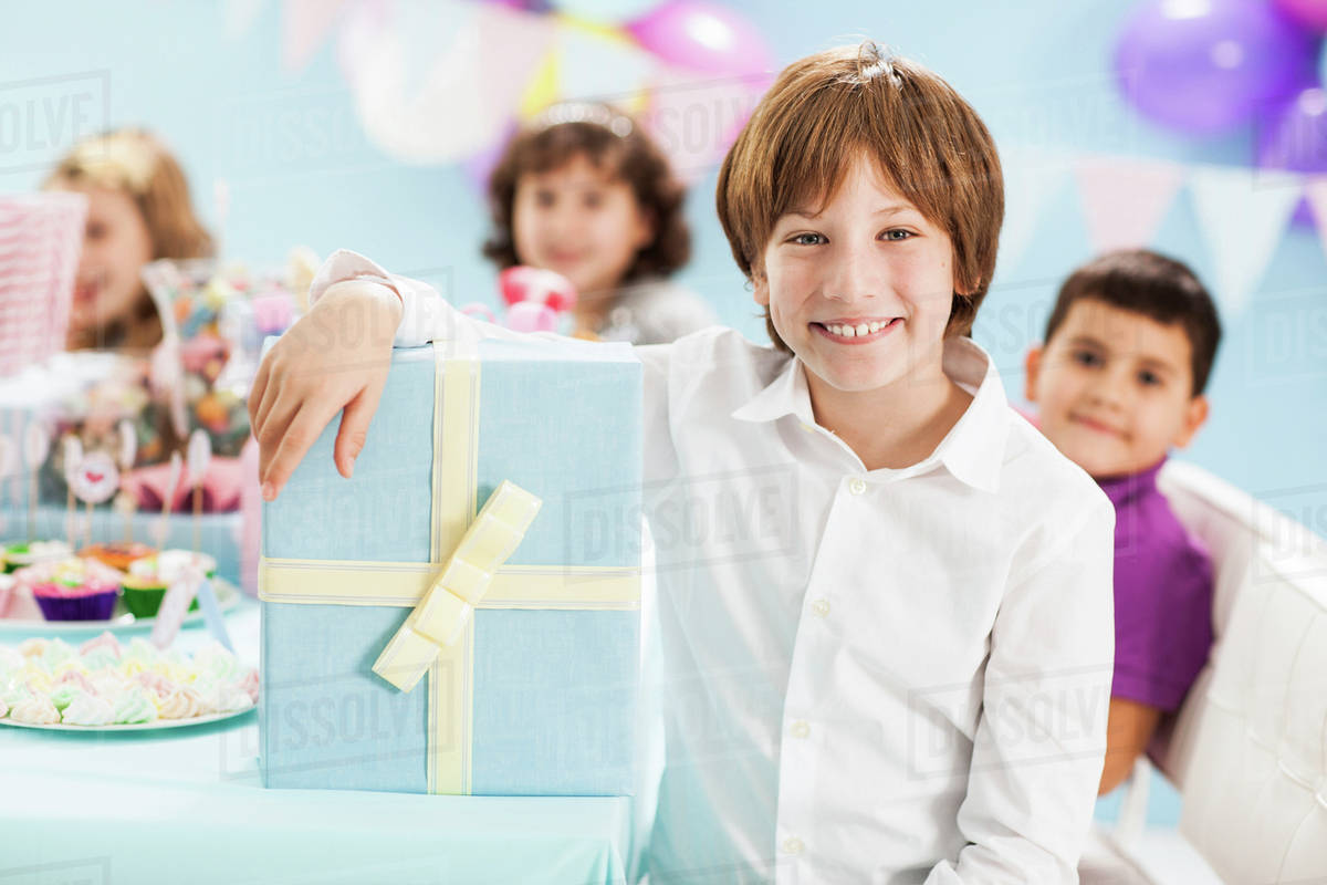 Boy smiling with wrapped gift at birthday party - Stock Photo - Dissolve