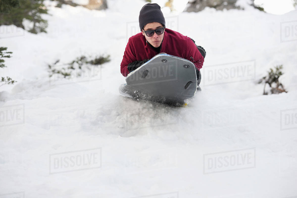 Hispanic man sledding on snowy hillside - Royalty-free Stock Photo ...