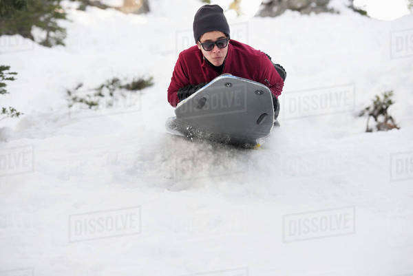 Hispanic man sledding on snowy hillside - Royalty-free Stock Photo ...