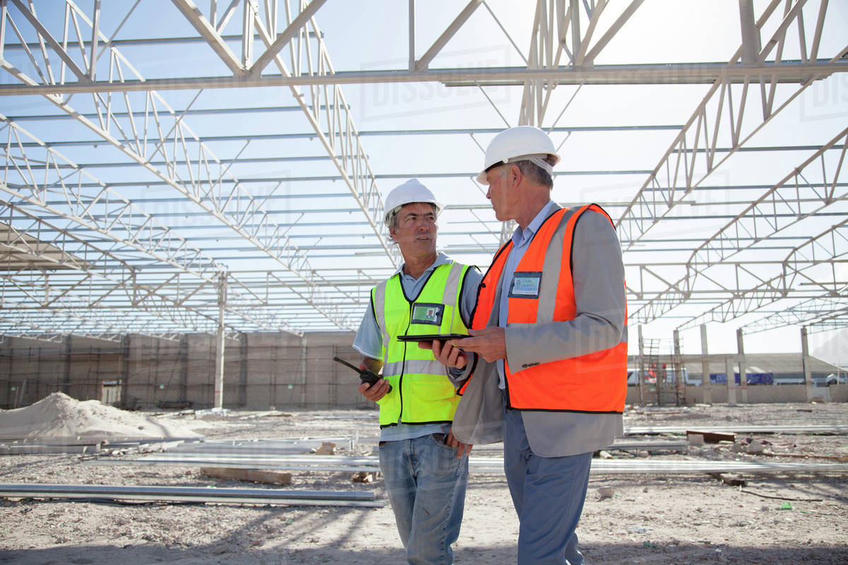 Caucasian architects talking at construction site - Stock Photo - Dissolve