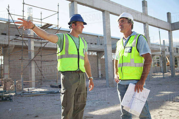 Caucasian construction workers talking at construction site - Royalty ...