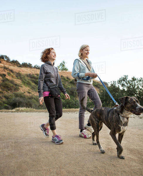 Caucasian women walking dog on dirt path - Royalty-free Stock Photo ...