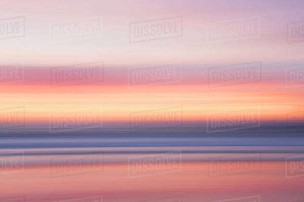 Defocused view of ocean waves on beach under sunset sky - Royalty-free ...