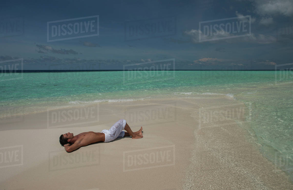 Caucasian man laying on beach - Stock Photo - Dissolve