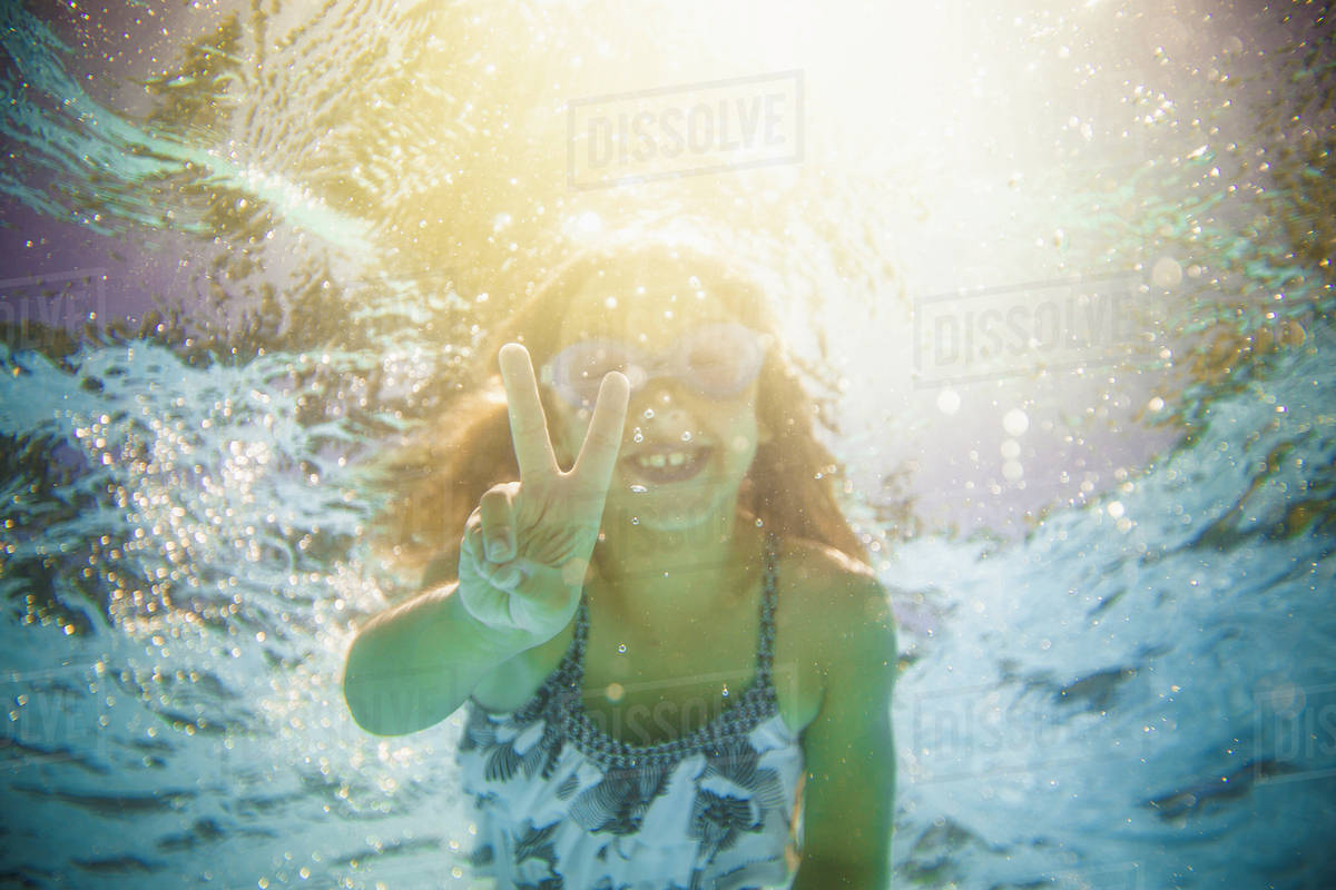Caucasian girl swimming underwater gesturing peace sign - Royalty-free ...