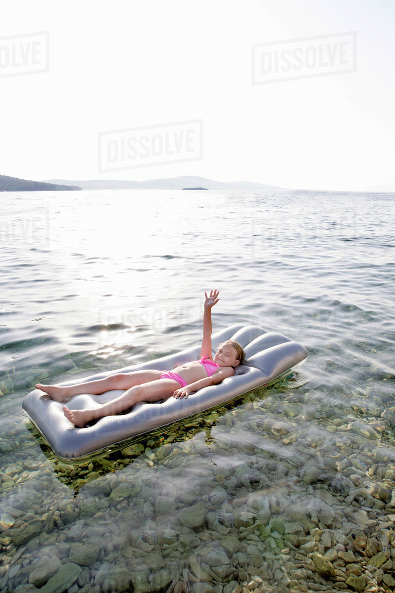Caucasian girl floating on raft in lake - Stock Photo - Dissolve