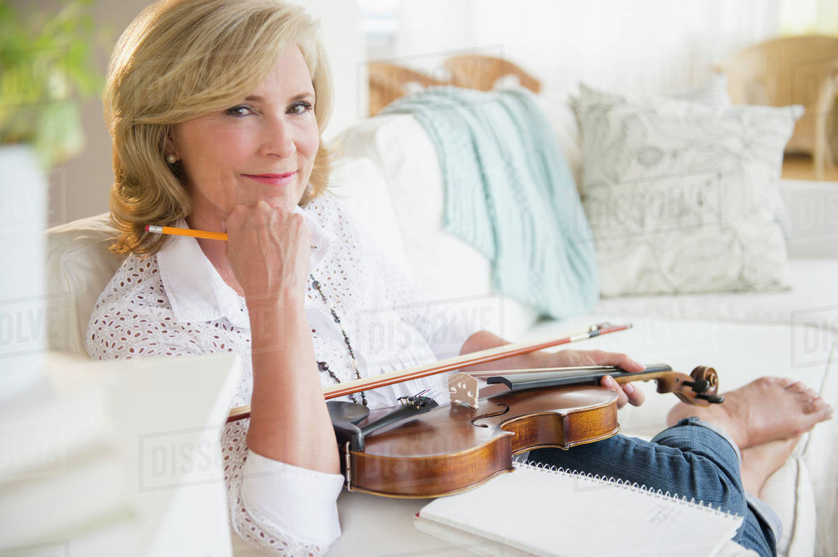 Caucasian woman holding violin on sofa - Stock Photo - Dissolve