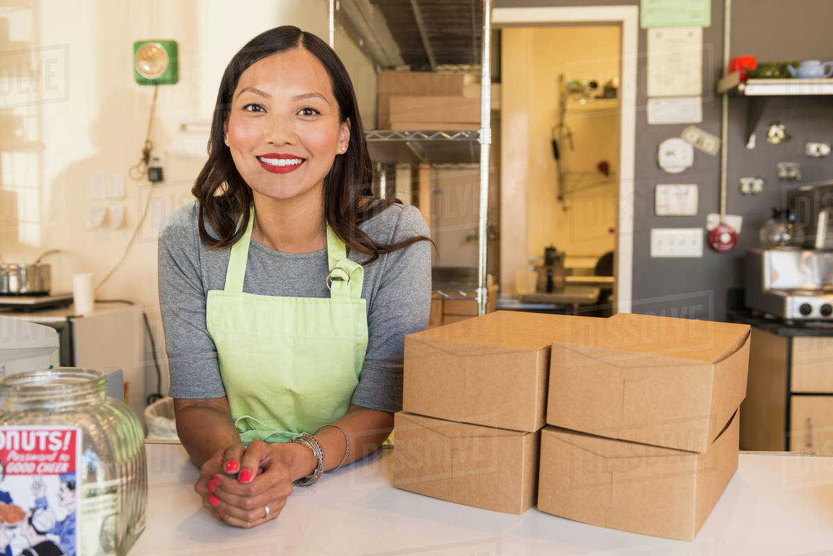 Asian baker smiling in bakery - Stock Photo - Dissolve