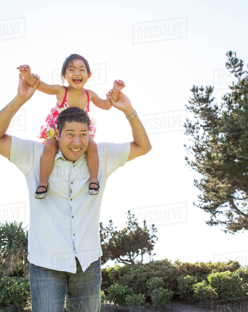 Hispanic father carrying daughter on shoulders - Royalty-free Stock Photo | Dissolve