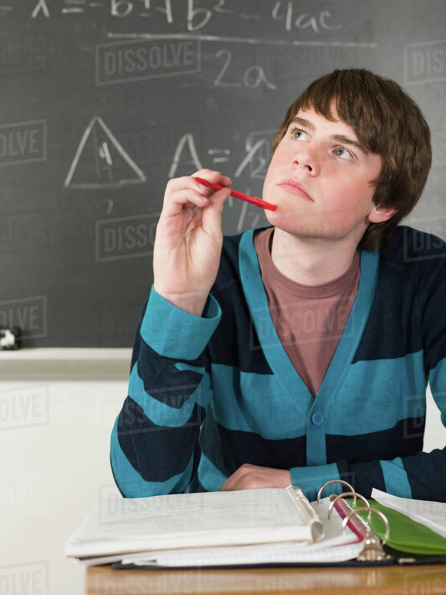 Student thinking at desk in classroom - Stock Photo - Dissolve