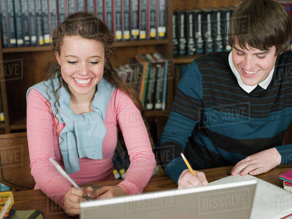 Students writing notes at desk in library - Stock Photo - Dissolve