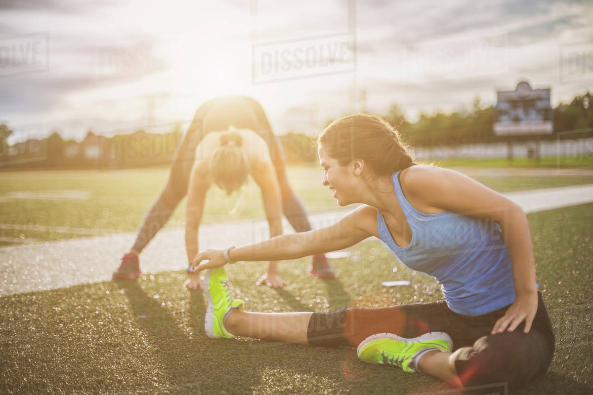 Athletes stretching on sports field - Stock Photo - Dissolve