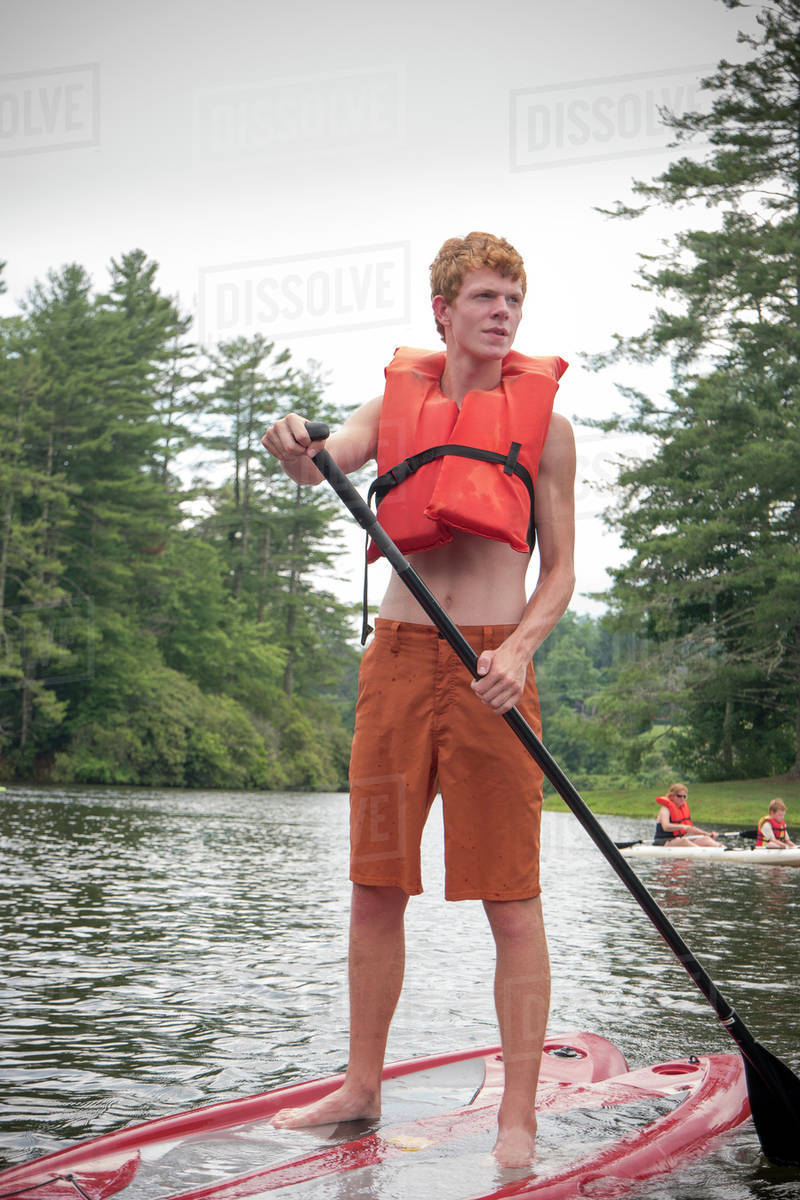 Caucasian teenage boy rowing paddleboat in lake - Royalty-free Stock ...