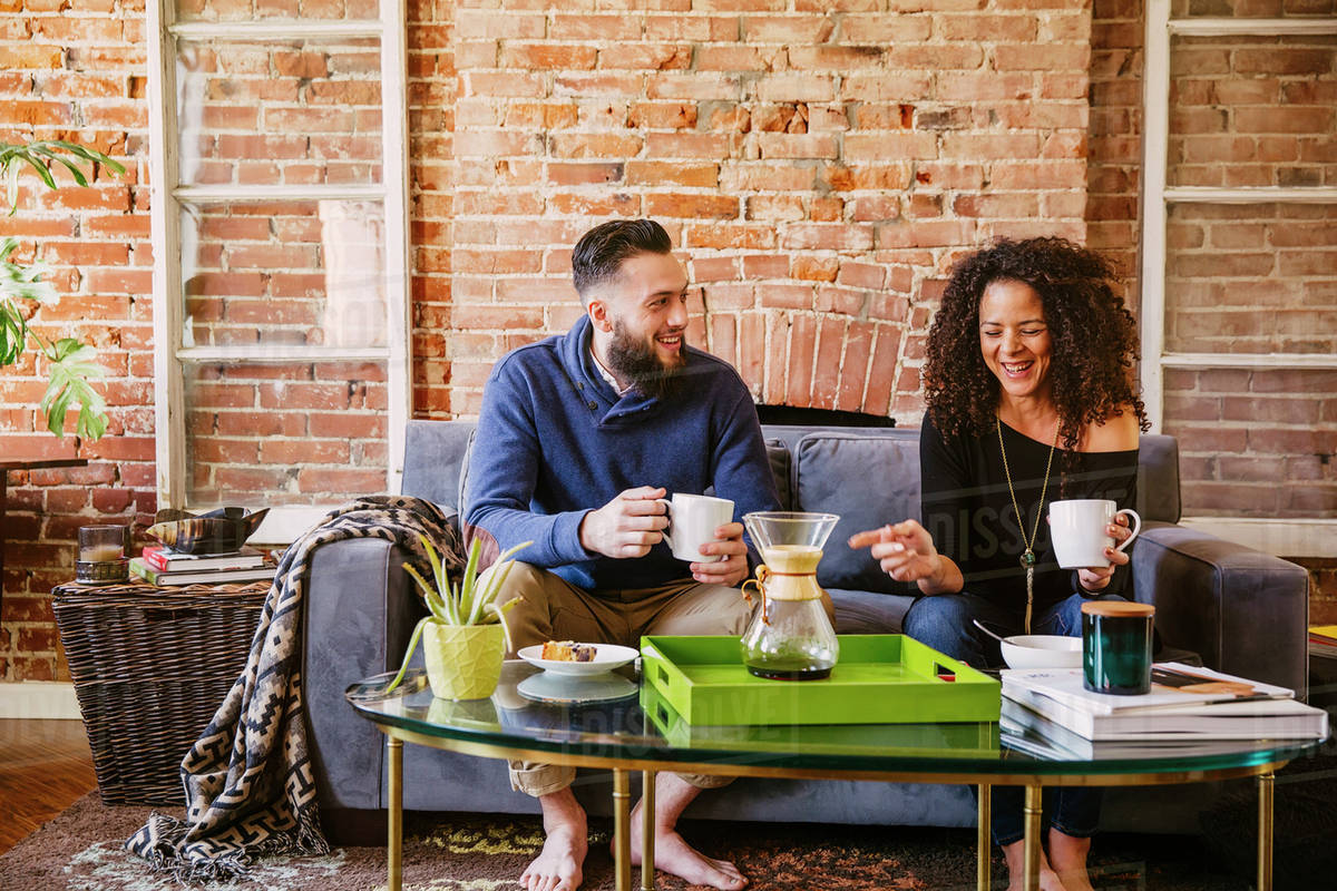 Couple drinking coffee on sofa in living room - Royalty-free Stock ...