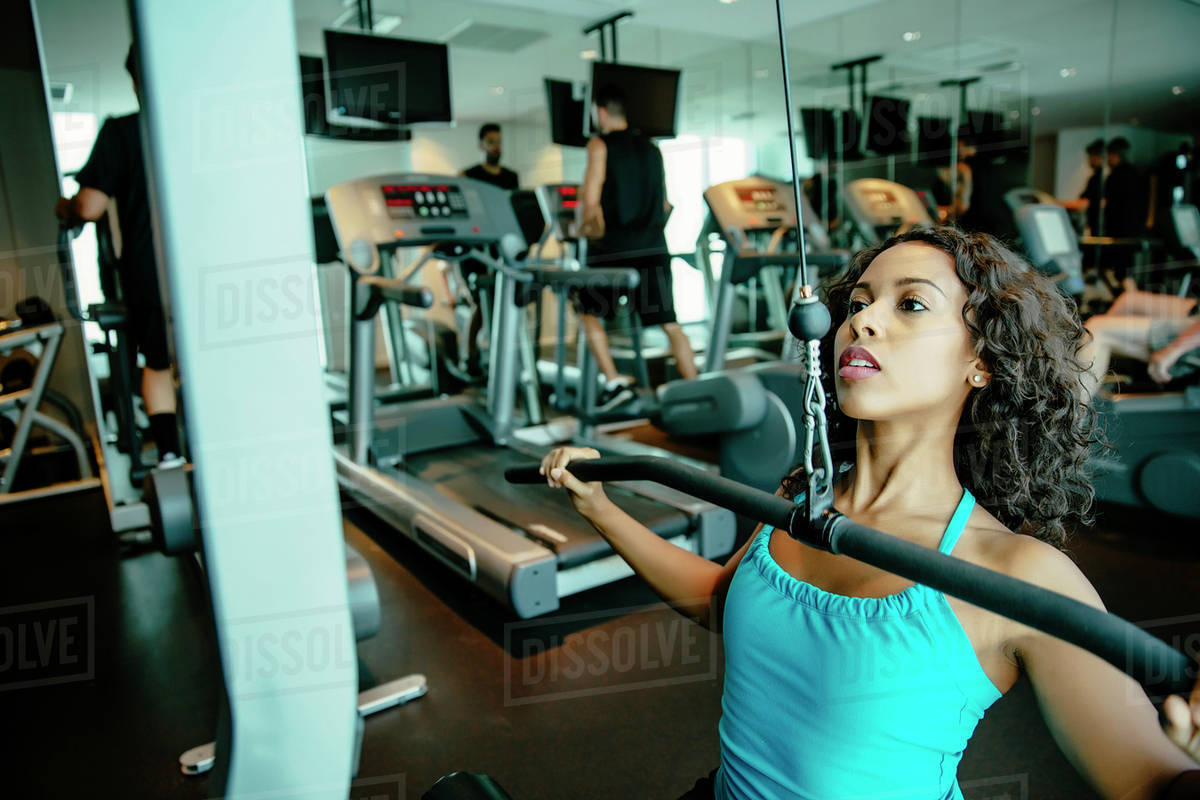 Woman using exercise machine in gymnasium - Royalty-free Stock Photo ...