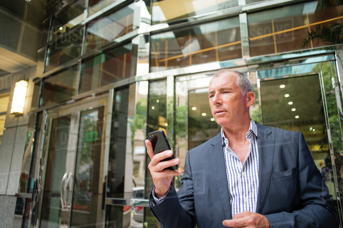 Caucasian businessman using cell phone outside office - Stock Photo ...
