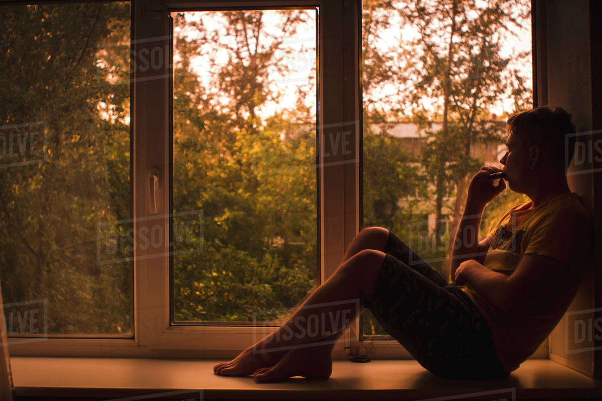 Caucasian man sitting in window sill - Stock Photo - Dissolve