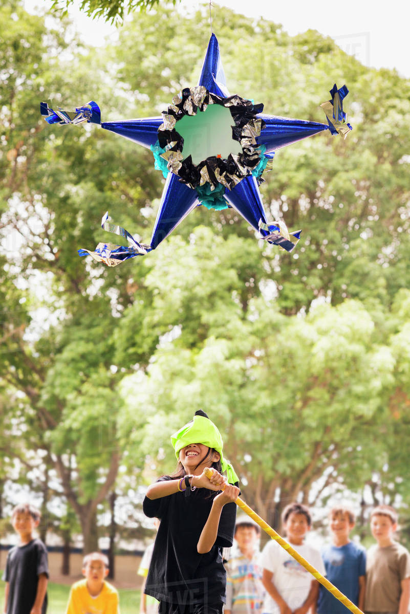 Blindfolded boy hitting pinata at party - Stock Photo - Dissolve