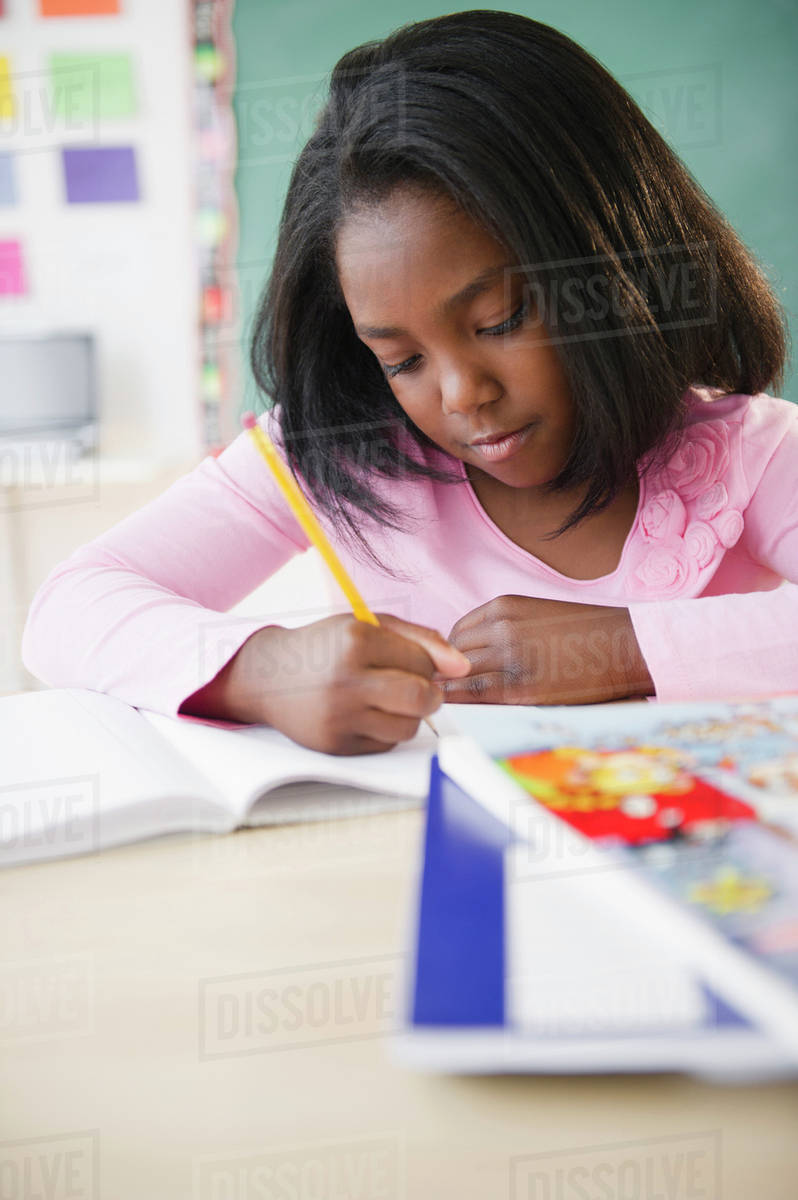 Black student writing in notebook in classroom - Royalty-free Stock ...