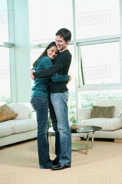 Couple hugging in living room - Royalty-free Stock Photo | Dissolve
