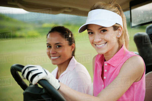 Women driving golf cart on golf course - Stock Photo - Dissolve