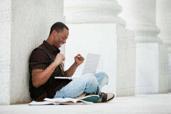 Black college student using laptop outdoors - Stock Photo - Dissolve